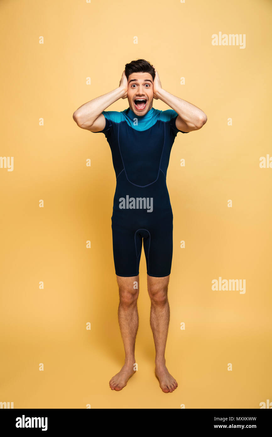 Photo of a shocked young man dressed in swimsuit isolated over yellow ...
