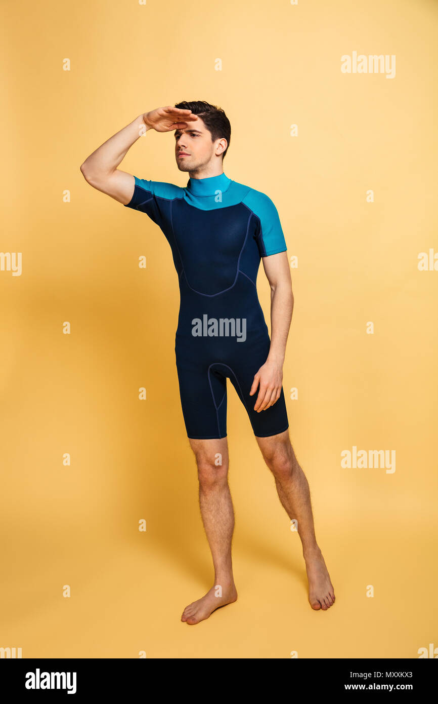 Full length portrait of a serious young man dressed in swimsuit looking ...