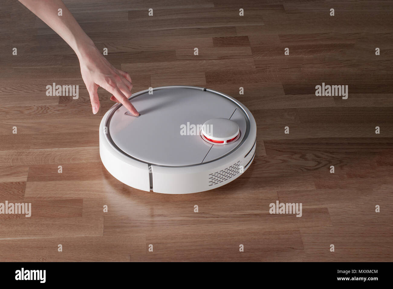 Woman clicks start button of robot vacuum cleaner. Modern smart ...