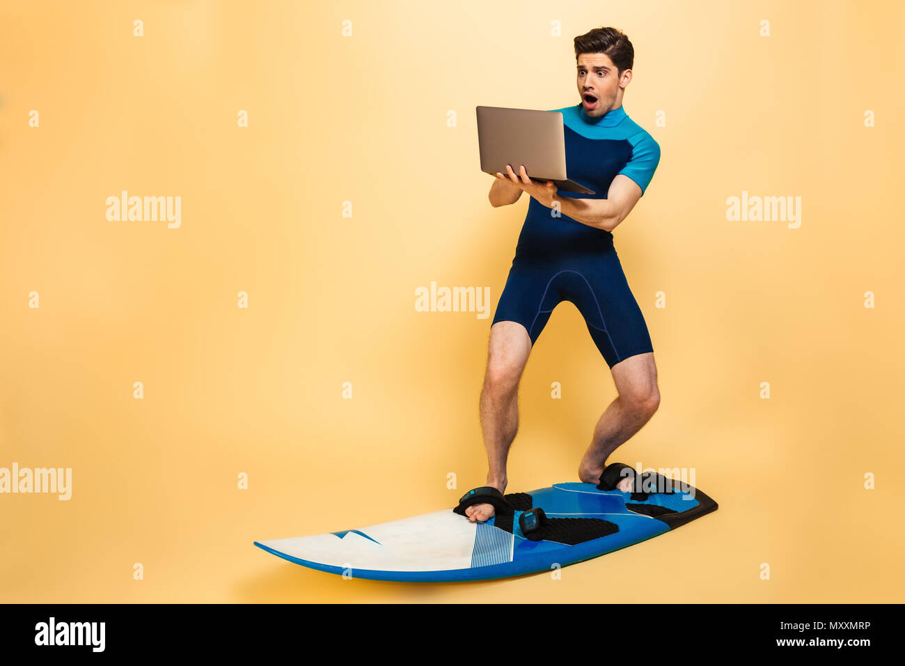 Full length portrait of a shocked young man dressed in swimsuit holding ...