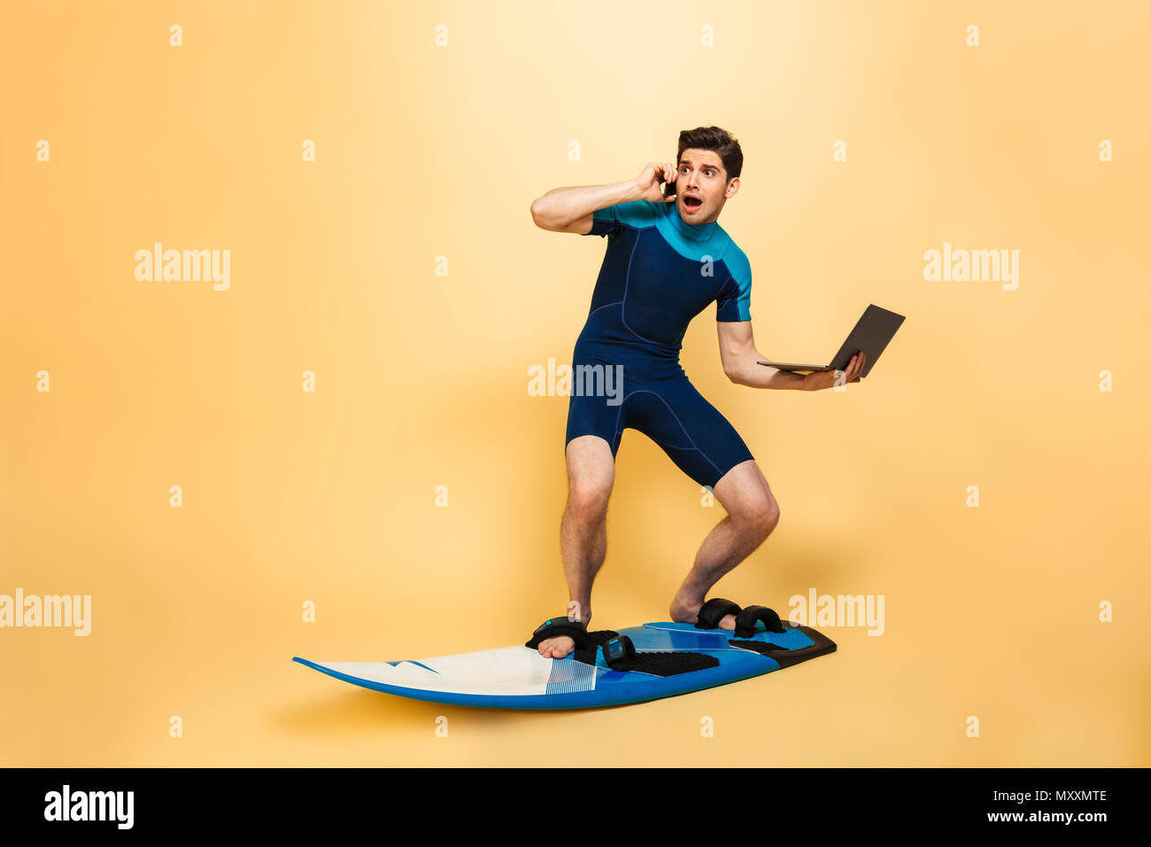 Full length portrait of a shocked young man dressed in swimsuit talking ...