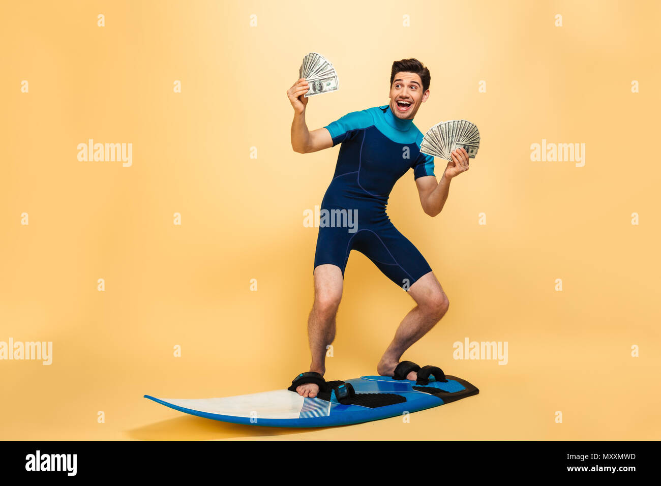 Full length portrait of a happy young man dressed in swimsuit holding ...