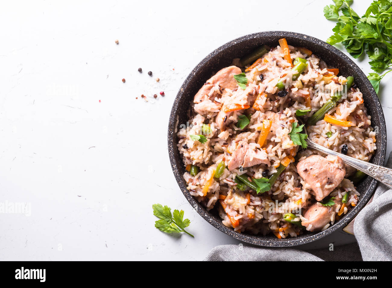 Pilaf with turkey meat, vegetables and brown rice on white table. Top ...