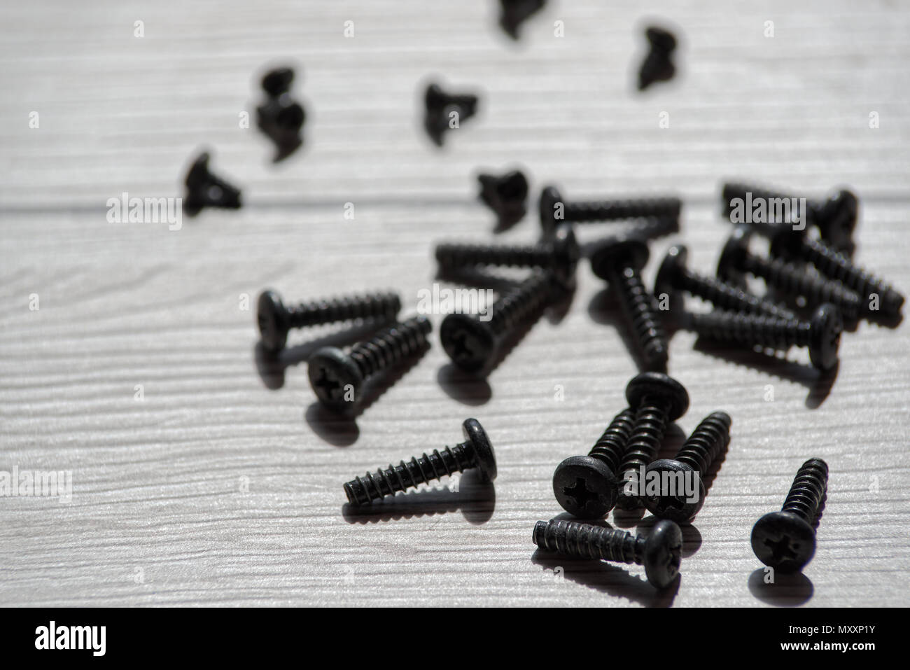 Small black screws are scattered on wooden background Stock Photo - Alamy
