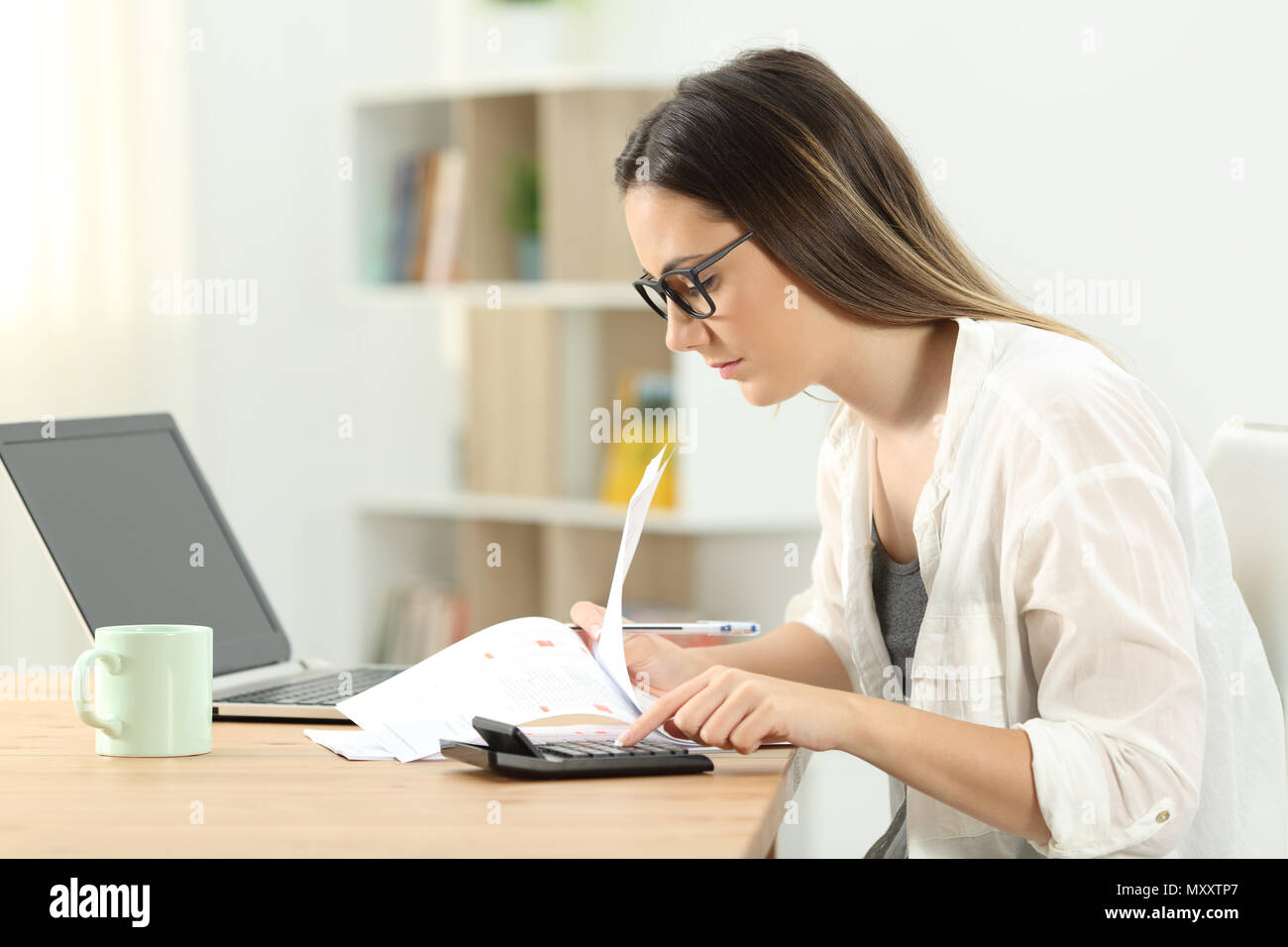 Side view portrait of a concentrated woman doing accounting at home ...