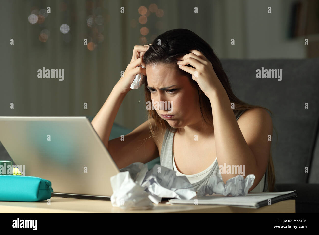Frustrated student studying on line late hours in the night at home ...