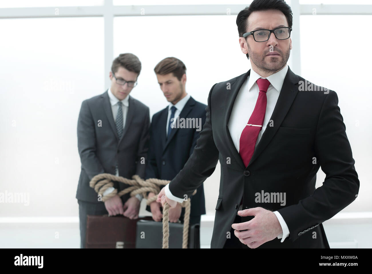 confident businessman pulls the rope tied employees Stock Photo - Alamy