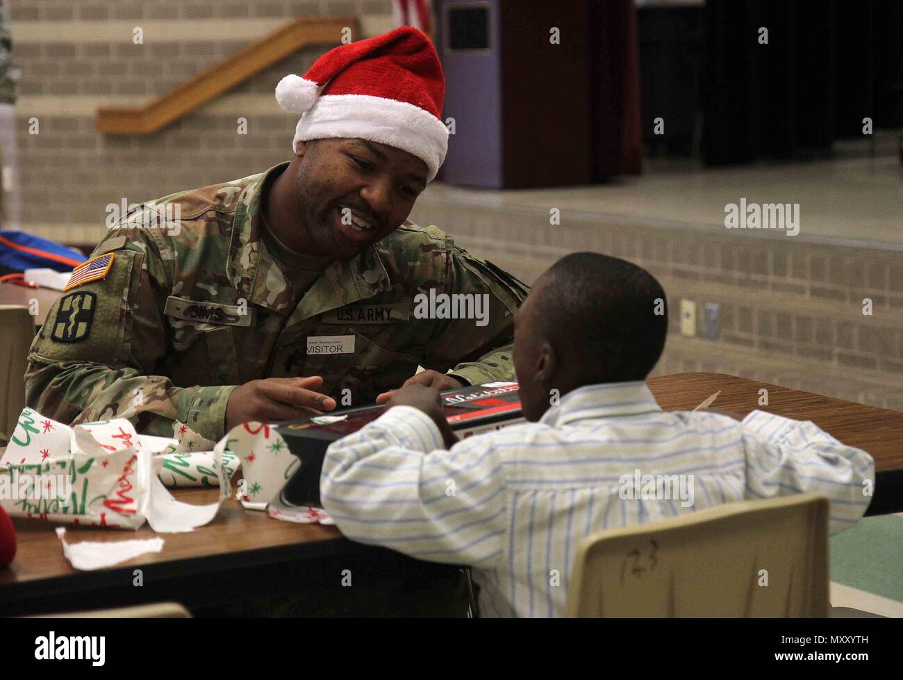 1st Lt. Inrico Sims helps a third-grade student open a gift donated ...