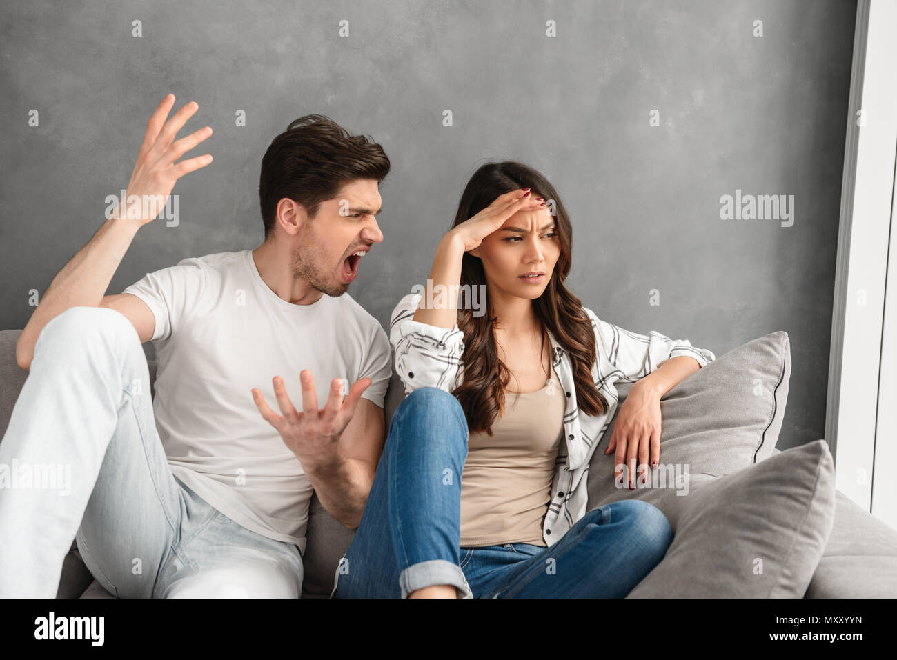 Photo of disappointed couple sitting together on sofa at home while man ...