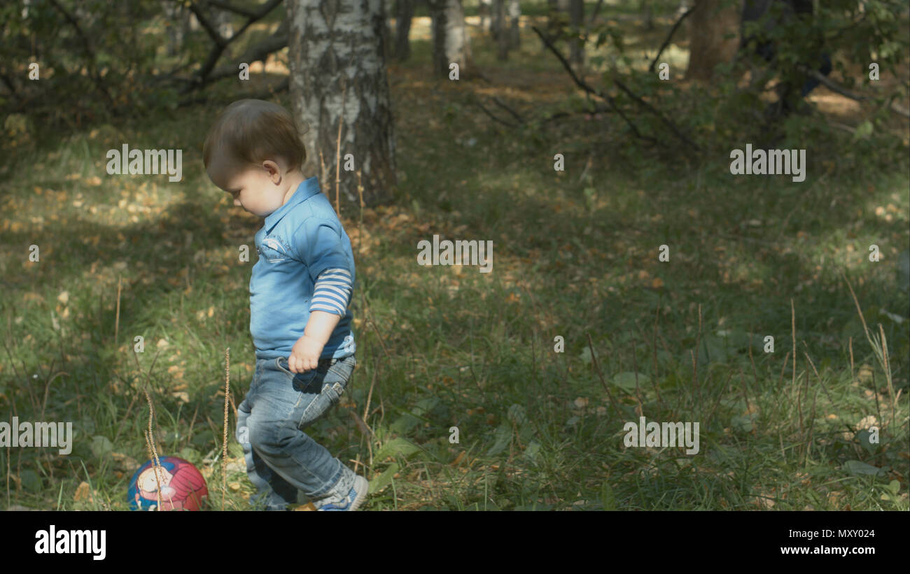 Little boy with pick up ball and throw Stock Photo - Alamy