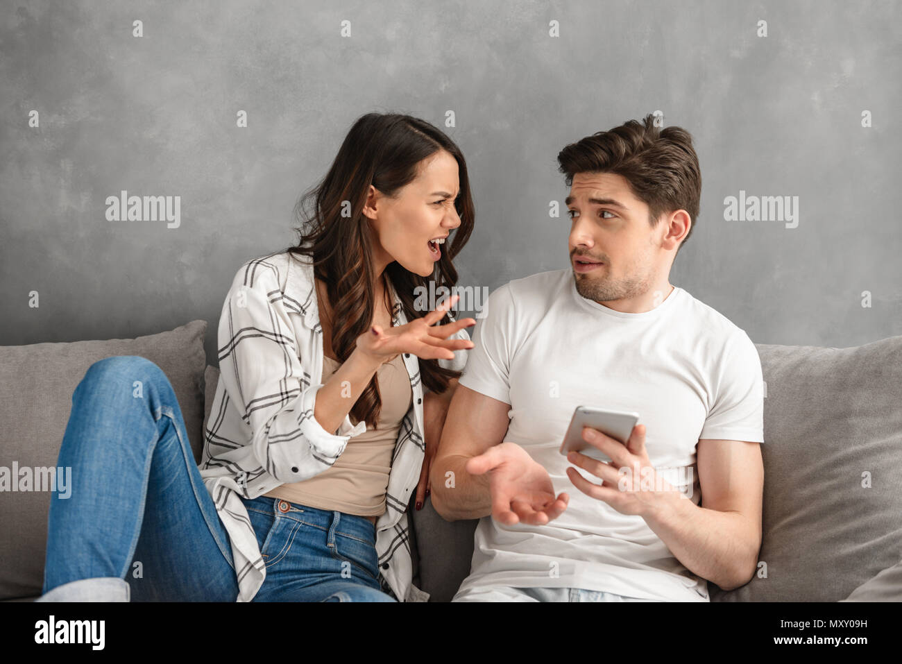 Fighting couple sitting together on sofa at home while woman shouting ...