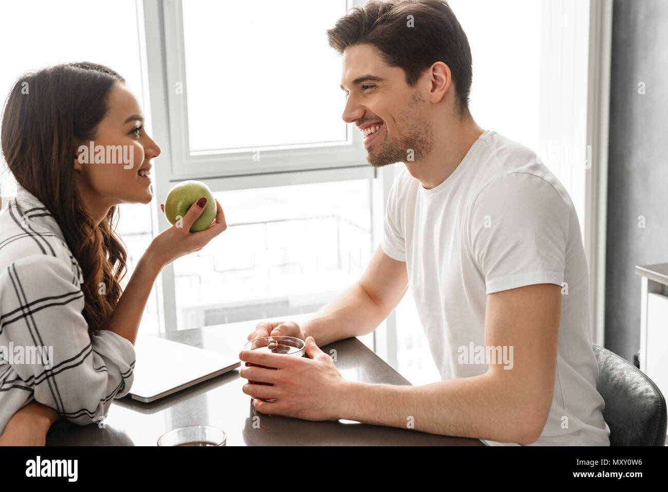 Image of attractive man and woman looking at each other while sitting ...