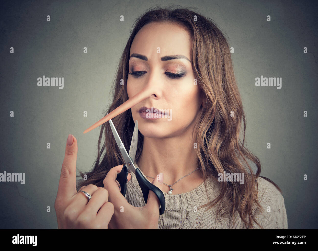 Girl having long nose of liar and trickster trying to change and cut ...