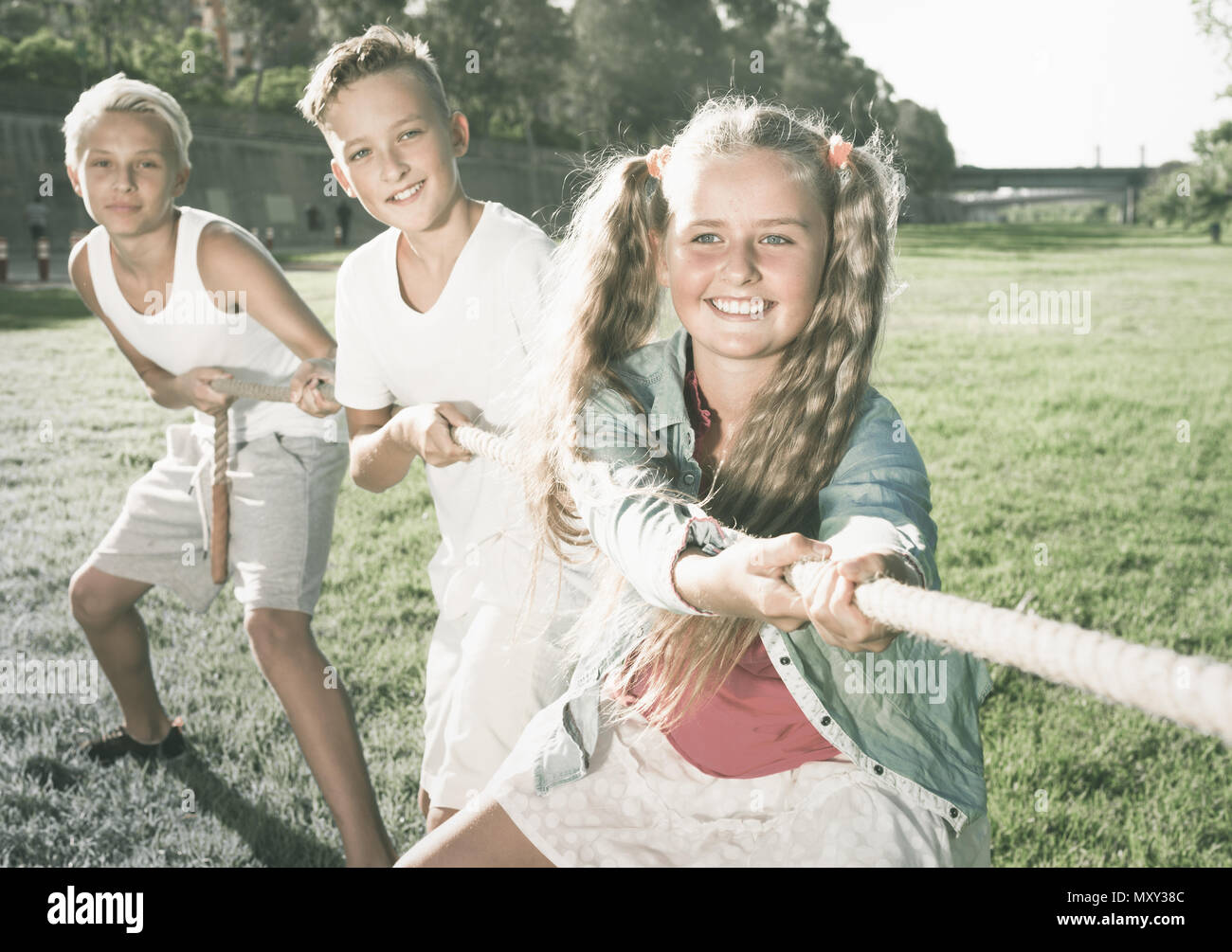 Children playing tug of war during joint games outdoors on sunny day ...