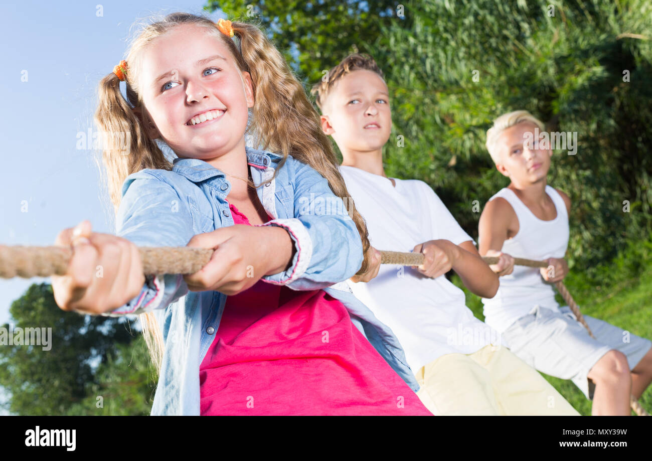Children playing tug of war during joint games outdoors on sunny day ...