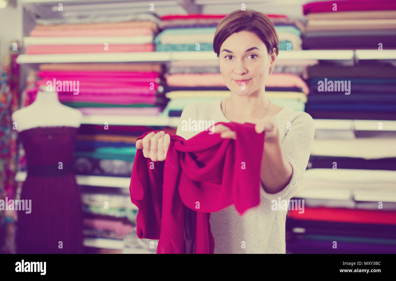 Young woman checking quality of fabric for dress at drapery shop Stock ...