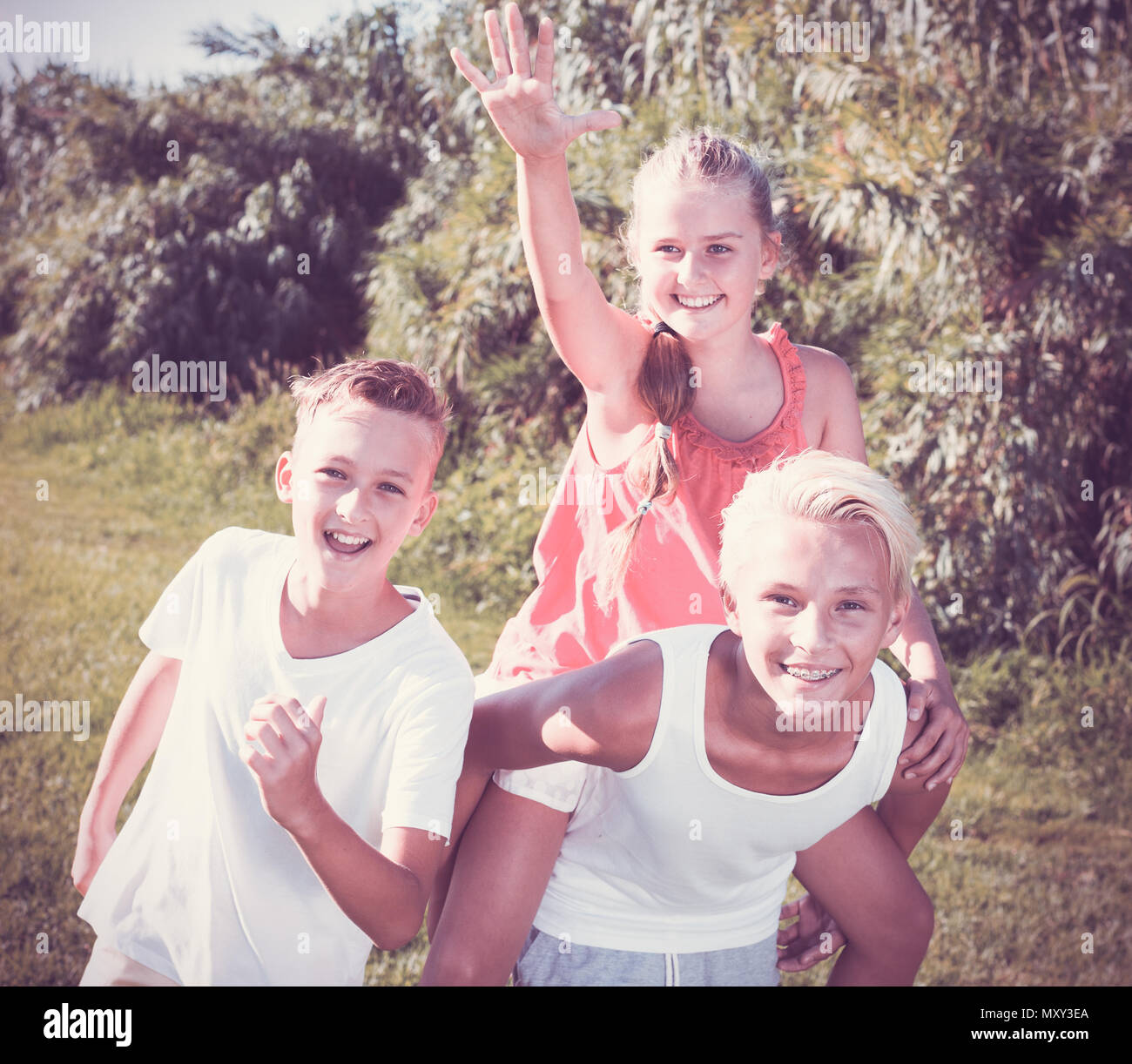 Happy children running together outdoors, boy carrying girl on back ...