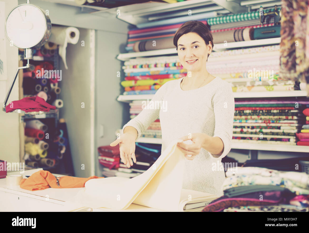 Female shop assistant demonstrating white fabric at drapery shop Stock ...