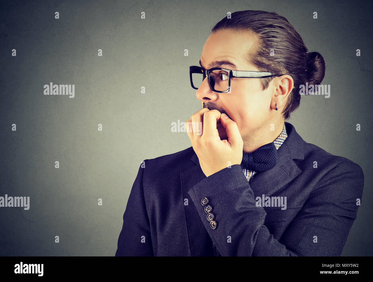 Preoccupied anxious young man biting his fingernails looking to the ...