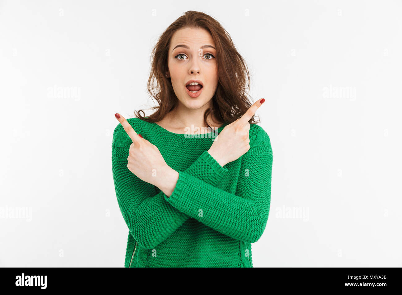 Portrait of a confused young woman pointing fingers at both sides ...