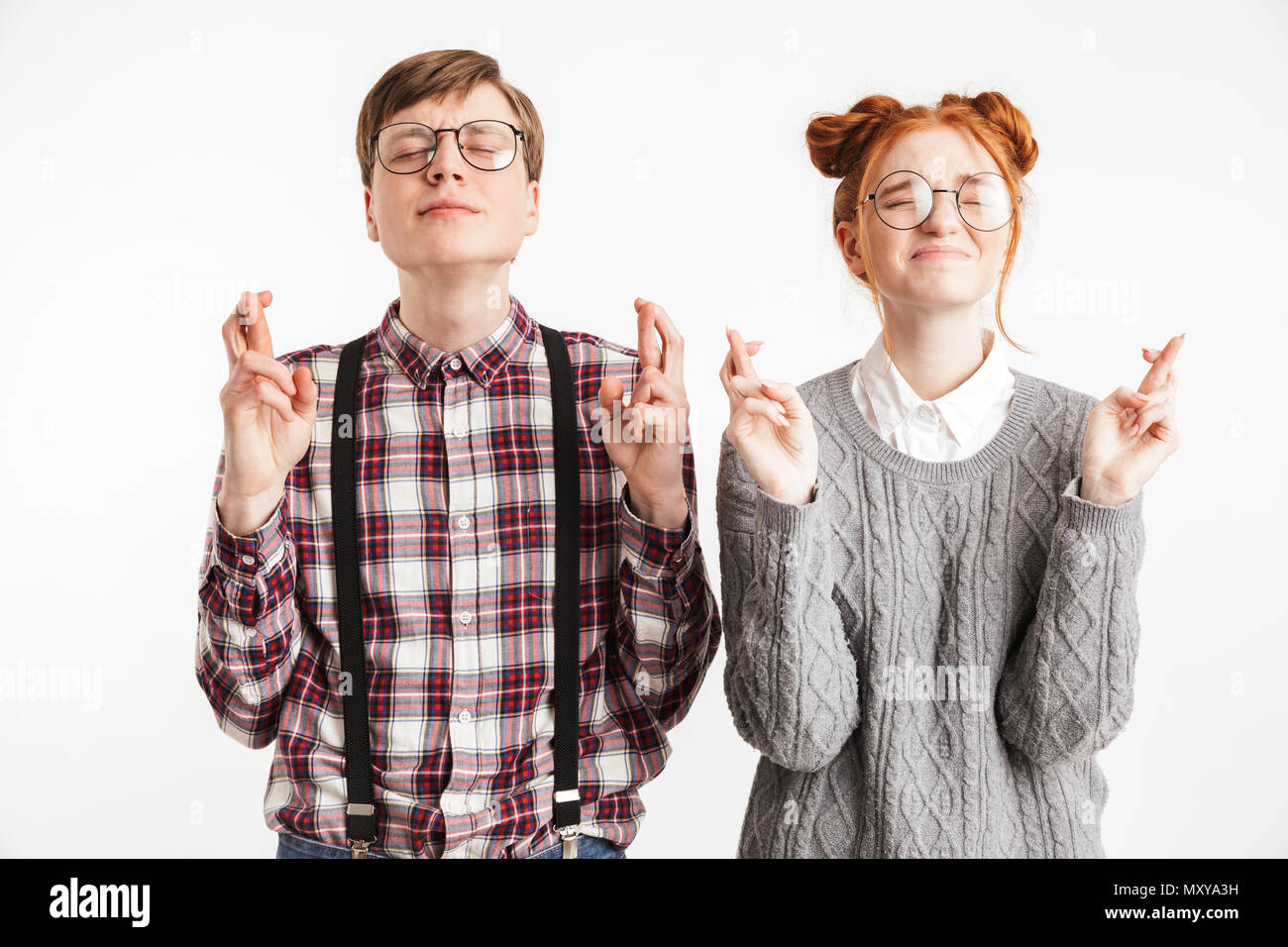 Pretty couple of school nerds holding crossed fingers for good luck ...