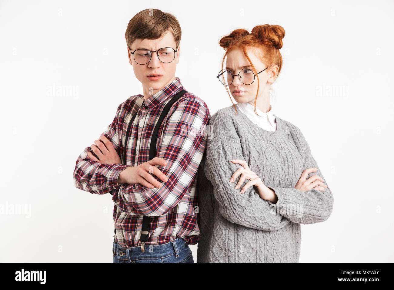 Upset couple of school nerds standing back to back isolated over white ...