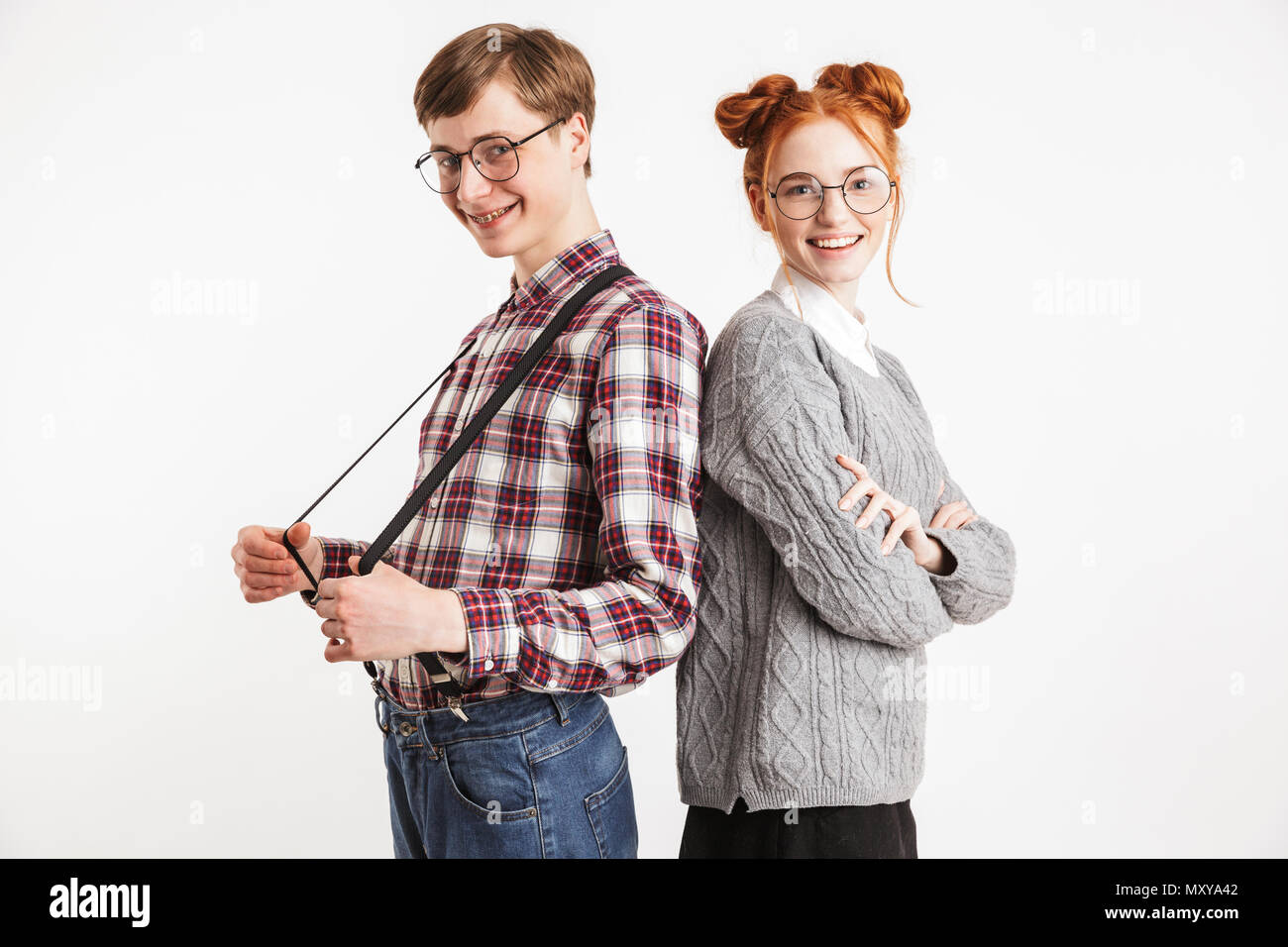 Smiling couple of school nerds standing back to back isolated over ...