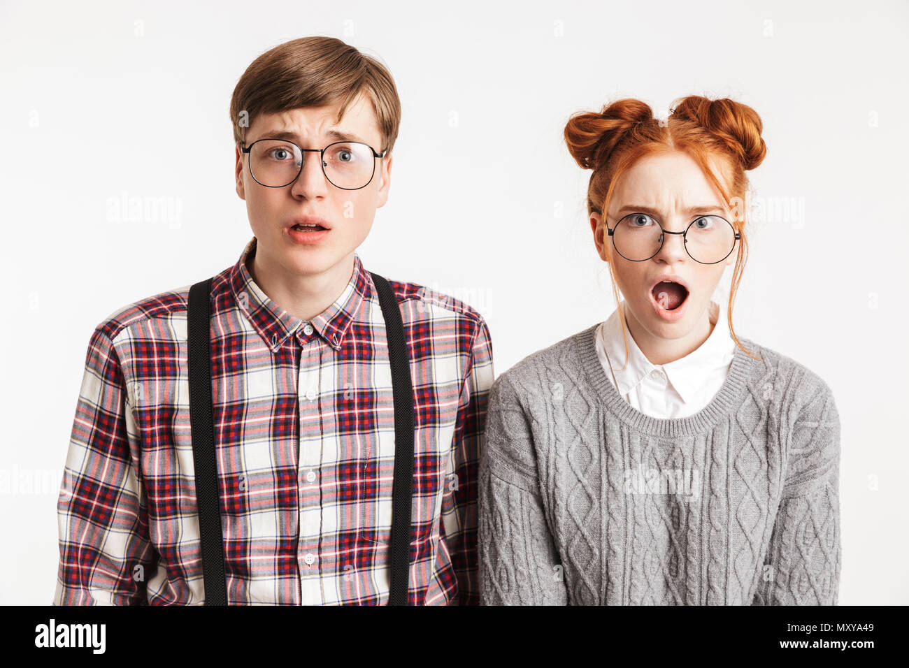 Shocked couple of school nerds looking at camera isolated over white ...