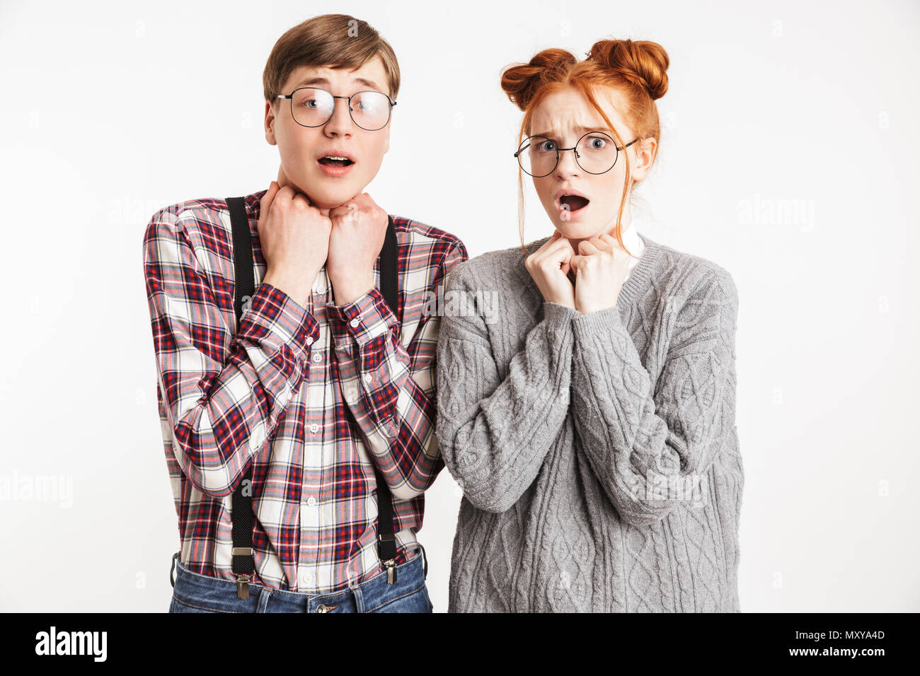 Scared couple of school nerds looking at camera isolated over white ...