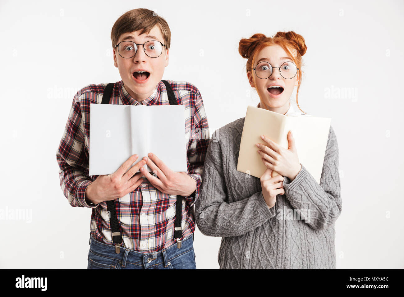 Surprised couple of school nerds holding books isolated over white ...