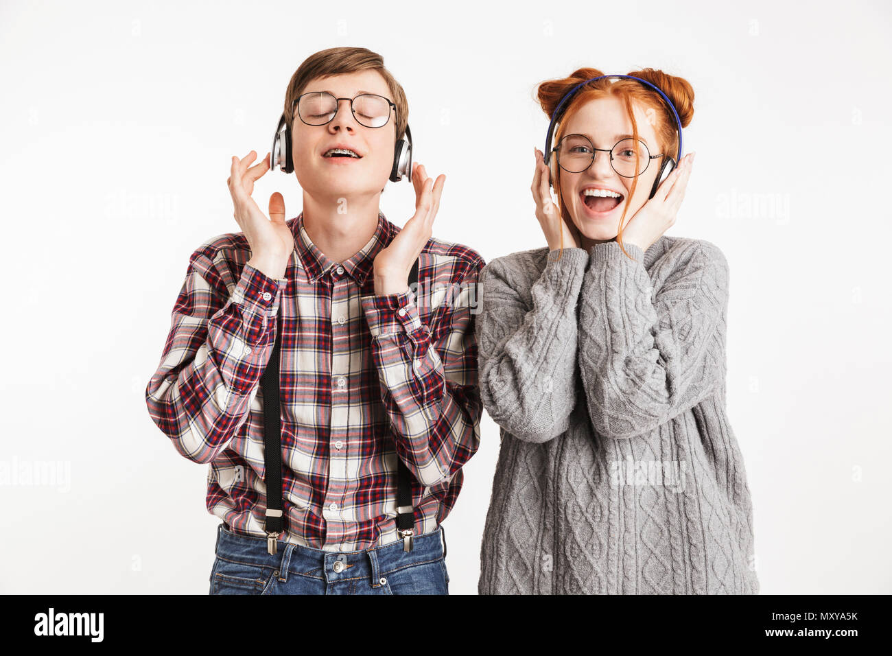 Happy couple of school nerds listening to music with headphones ...