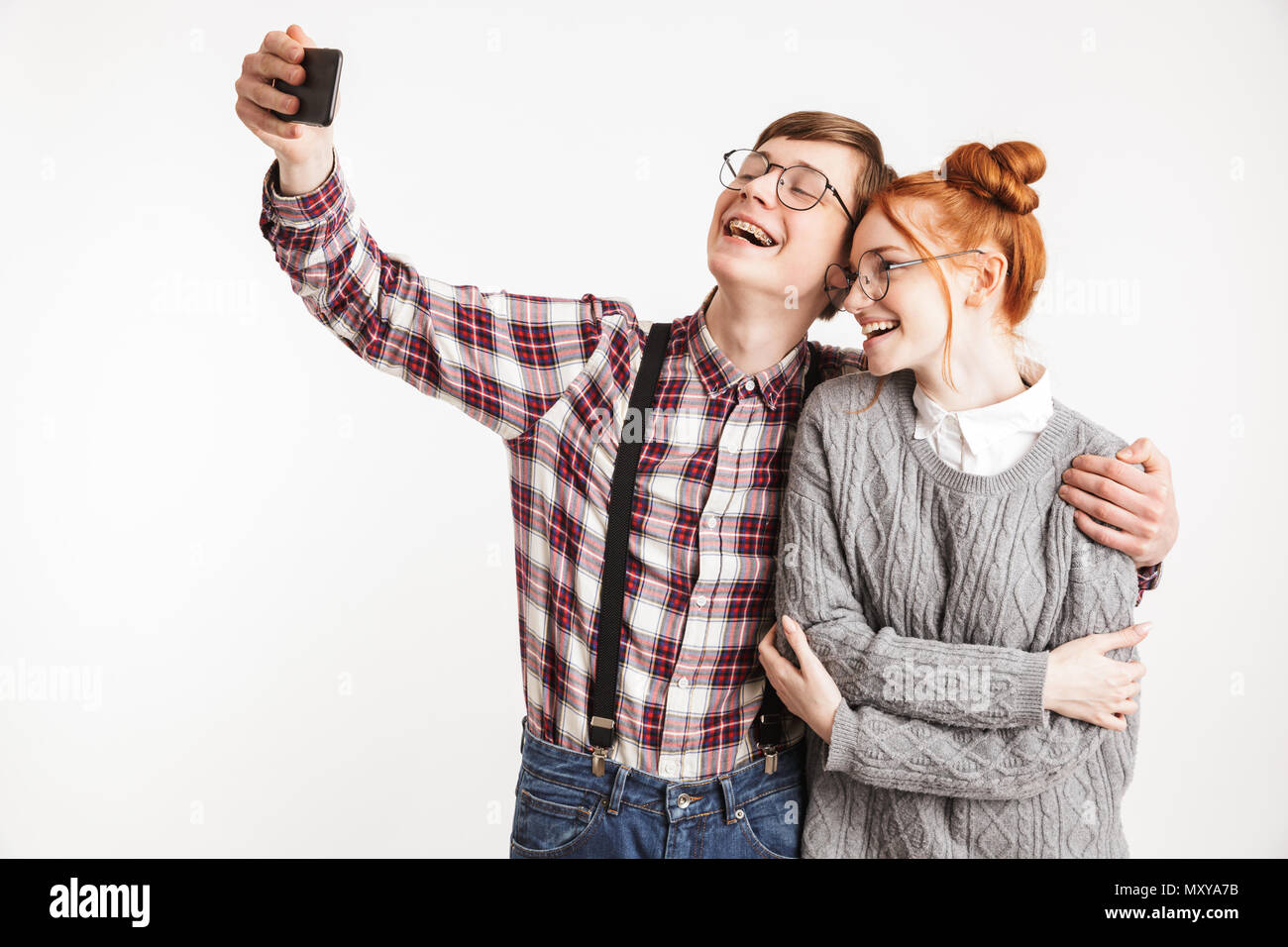 Happy couple of school nerds taking selfie with mobile phone isolated ...