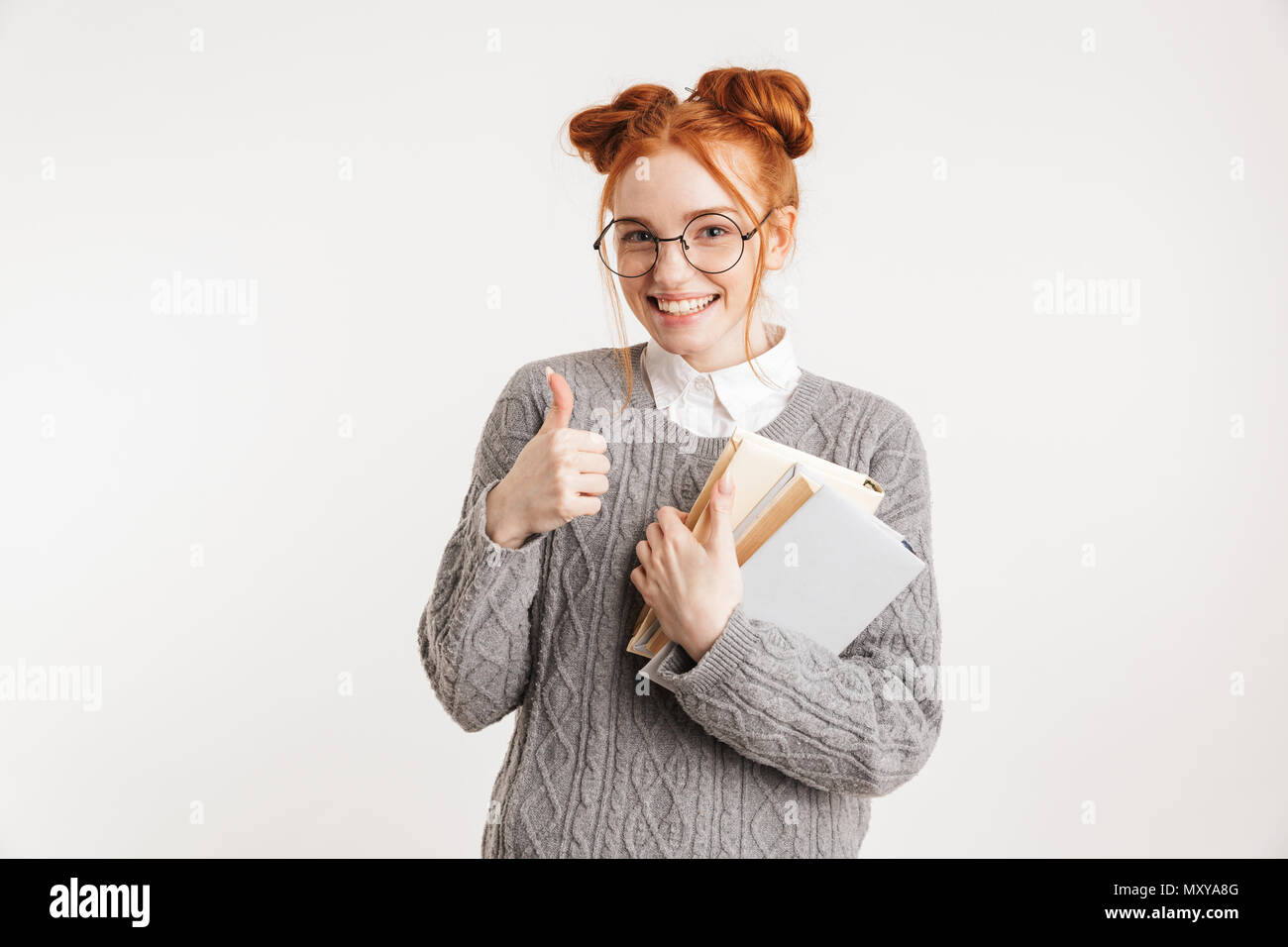 Portrait of a smiling young school nerd girl holding stack of books and ...