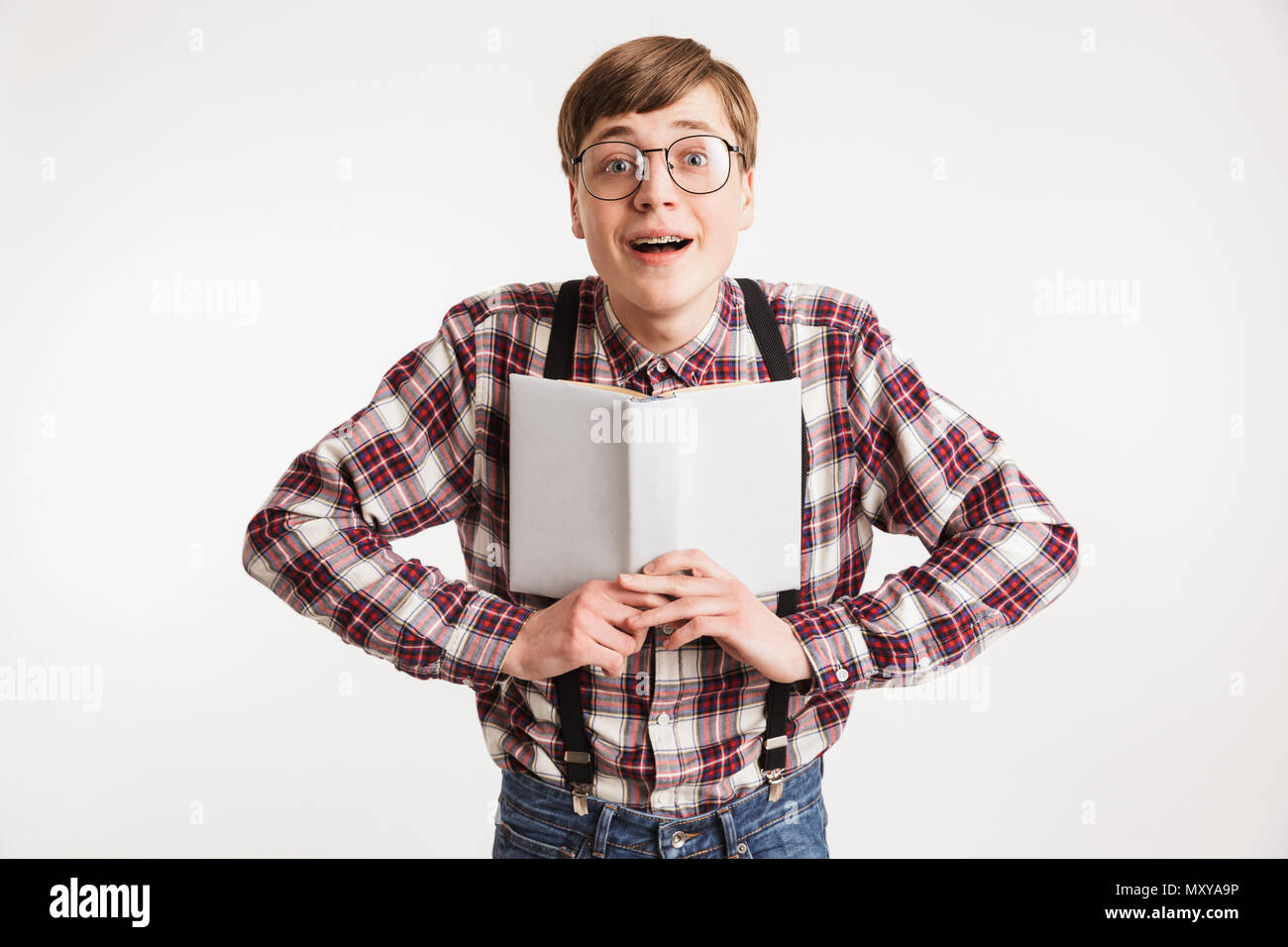 Portrait of an excited young school nerd guy holding book isolated over ...