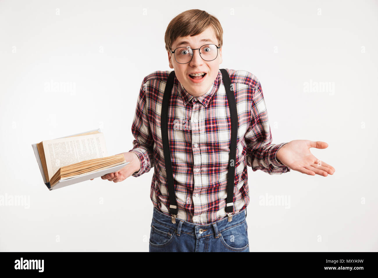 Portrait of a confused young school nerd guy holding book isolated over ...