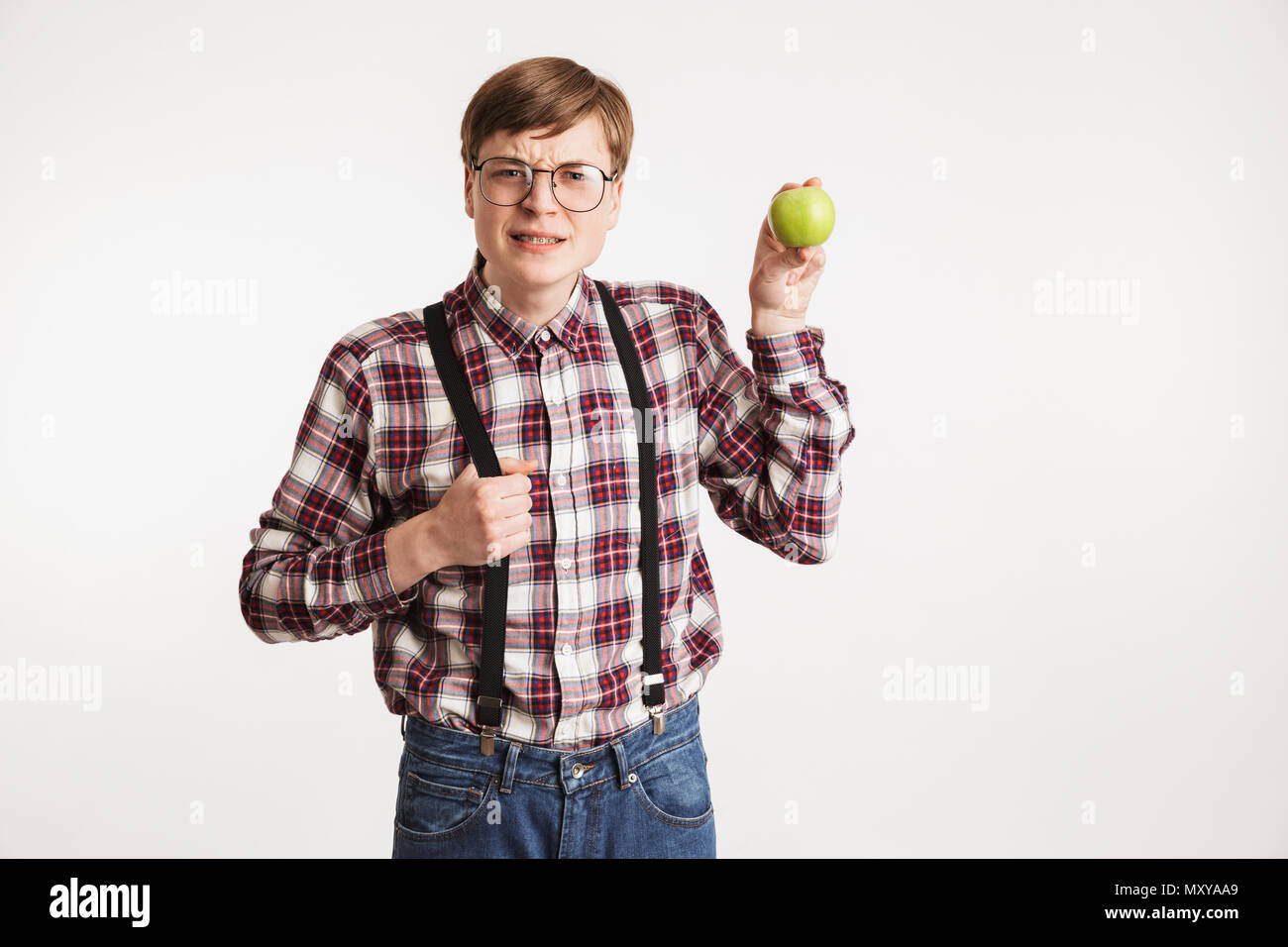 Portrait of a confused young school nerd guy holding an apple isolated ...