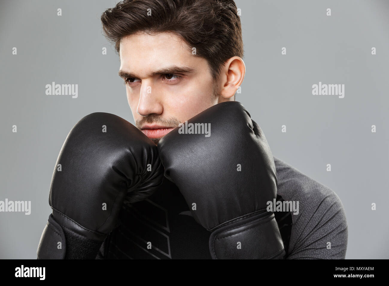 Image of concentrated young sportsman boxer standing isolated over grey ...