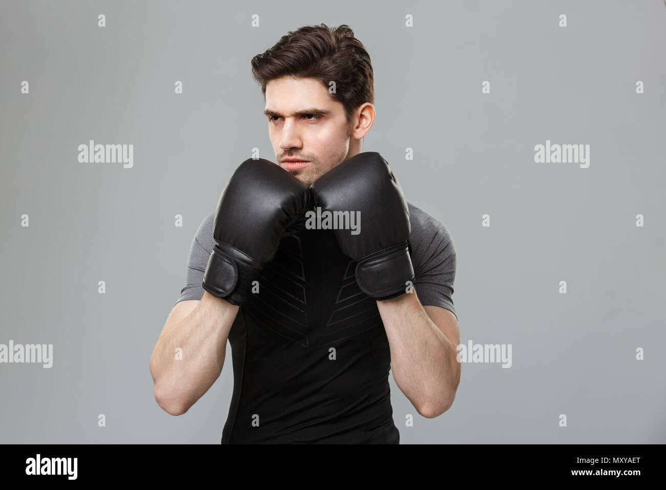 Image of concentrated young sportsman boxer standing isolated over grey ...