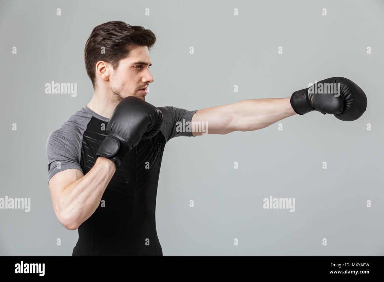Image of concentrated young sportsman boxer standing isolated over grey ...