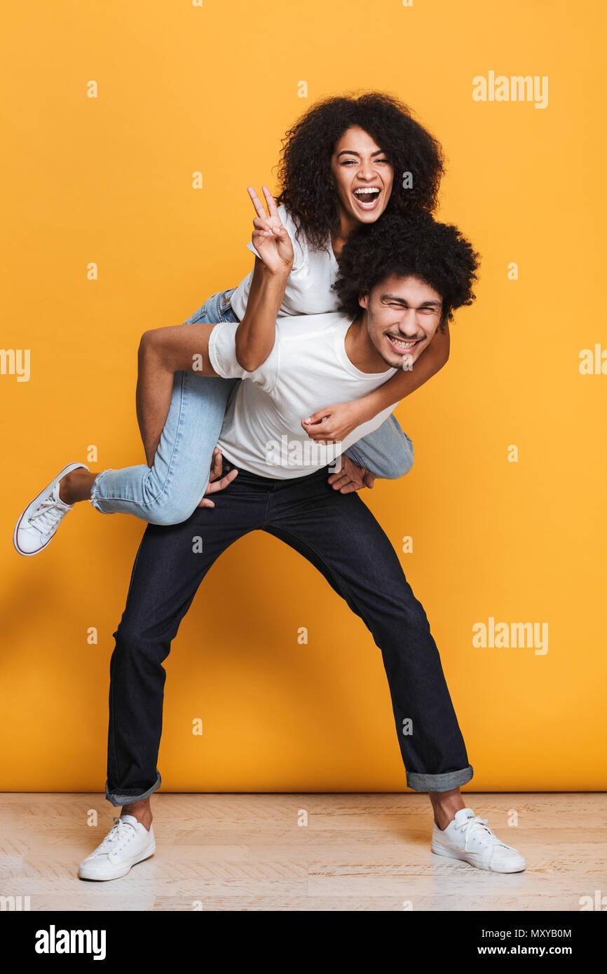 Full length portrait of a happy young african guy giving piggyback ride ...