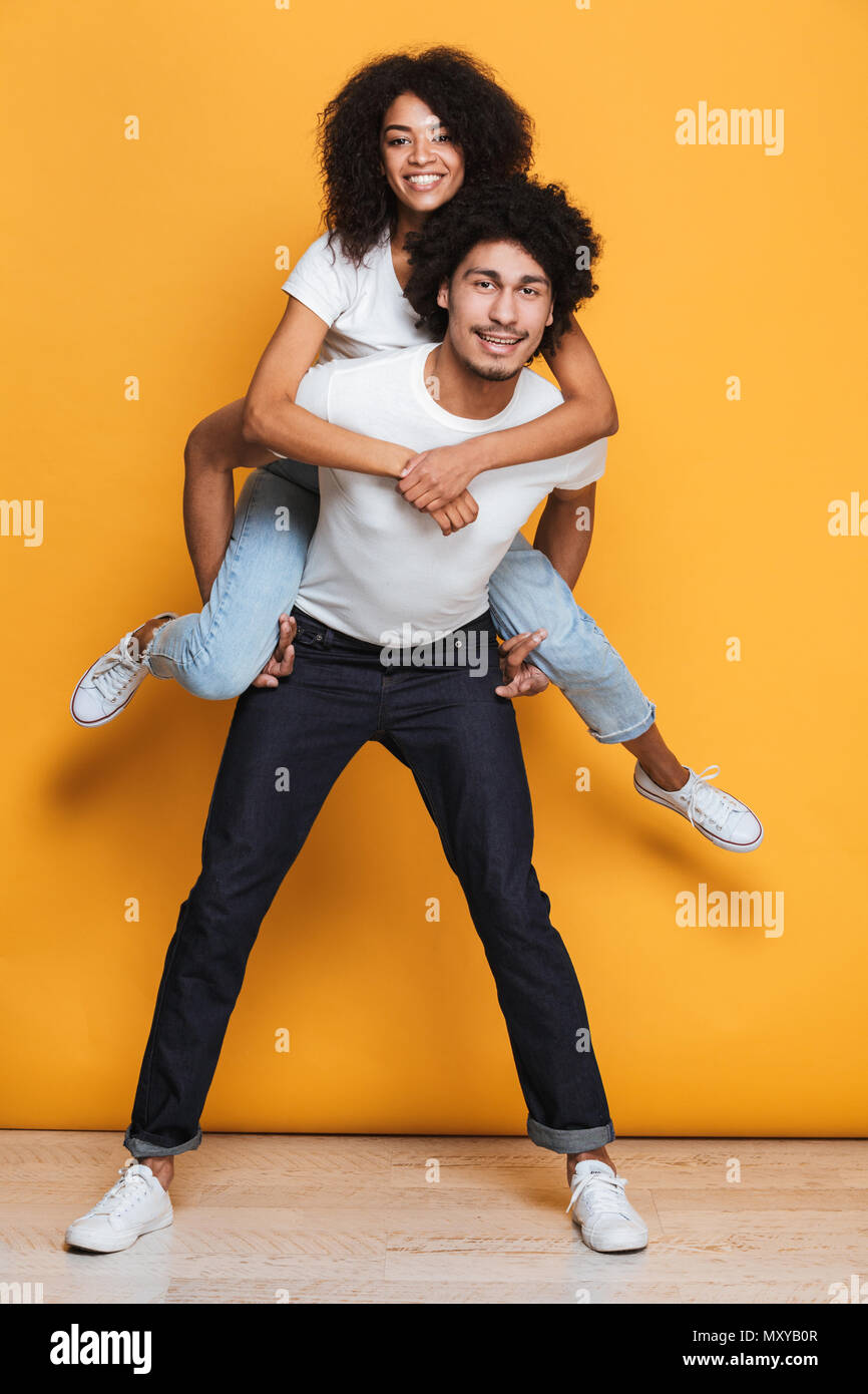 Full length portrait of a cheerful young african guy giving piggyback ...