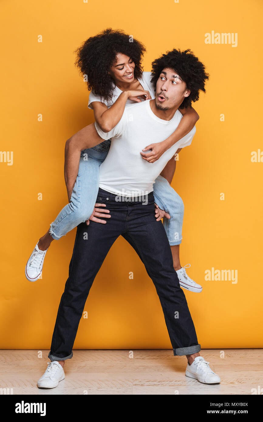 Full length portrait of a funny young african guy giving piggyback ride ...