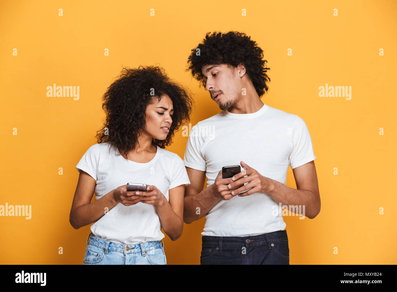 Portrait of a suspicious afro american couple with mobile phone ...