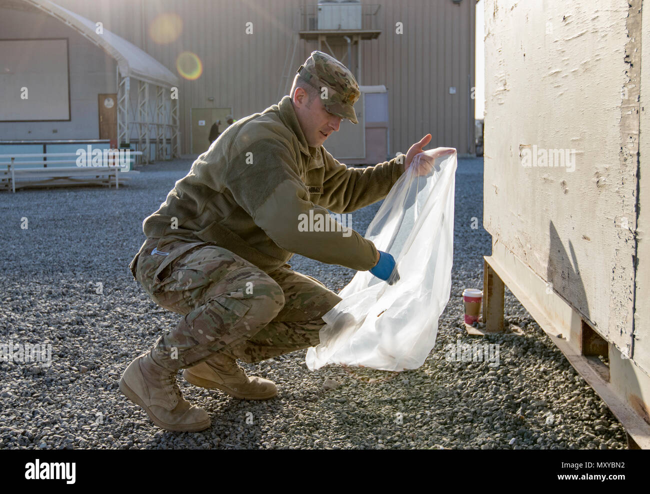 A U.S. Army Soldier picks up trash during an organized cleanup Dec. 16 ...