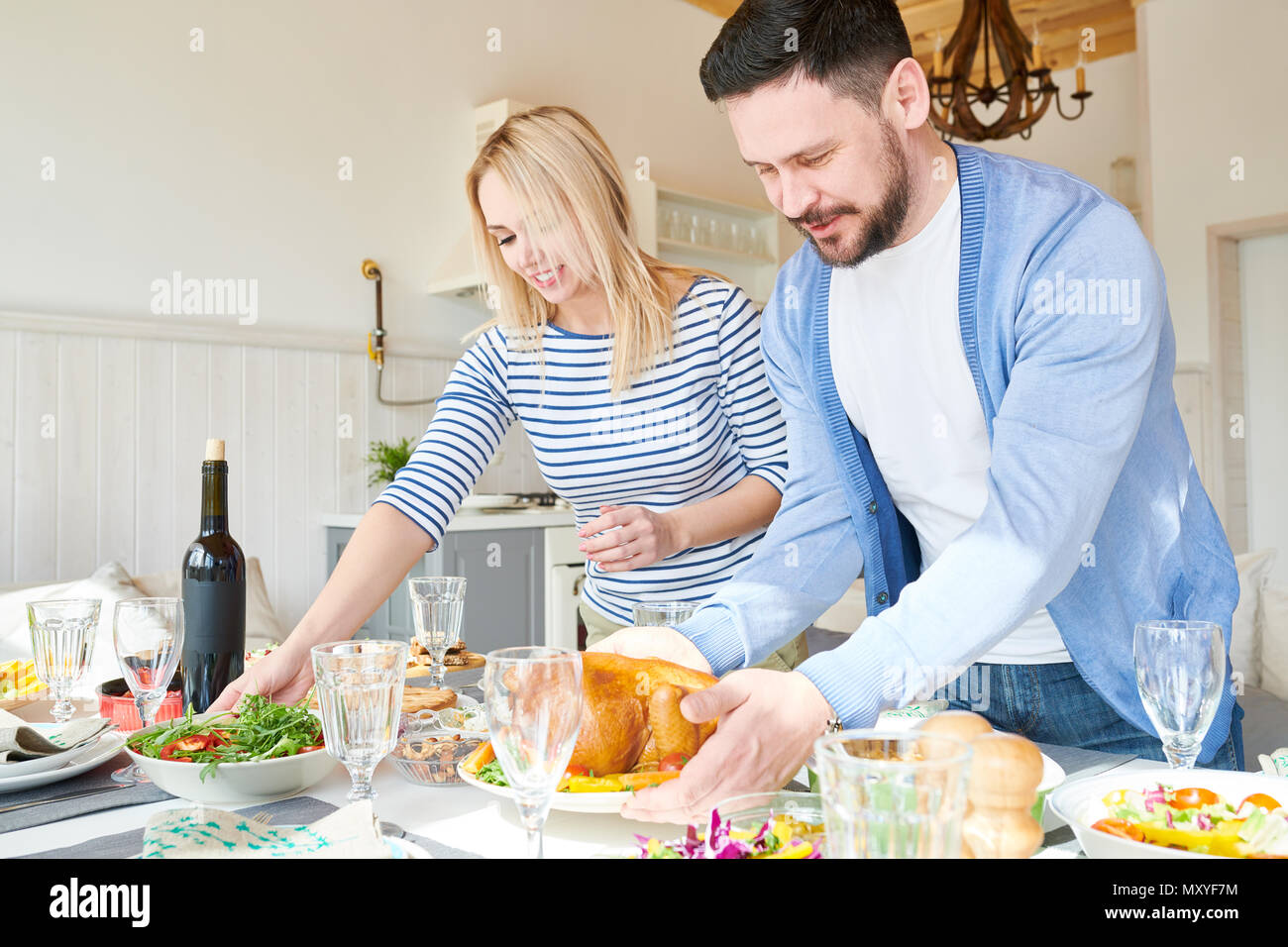 Portrait of modern young couple setting dinner table while waiting for ...