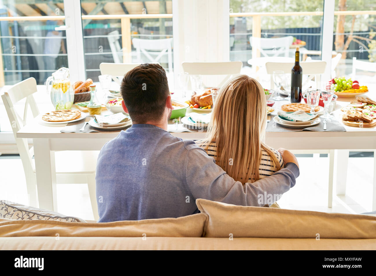 Back view portrait of successful young couple sitting on couch by ...