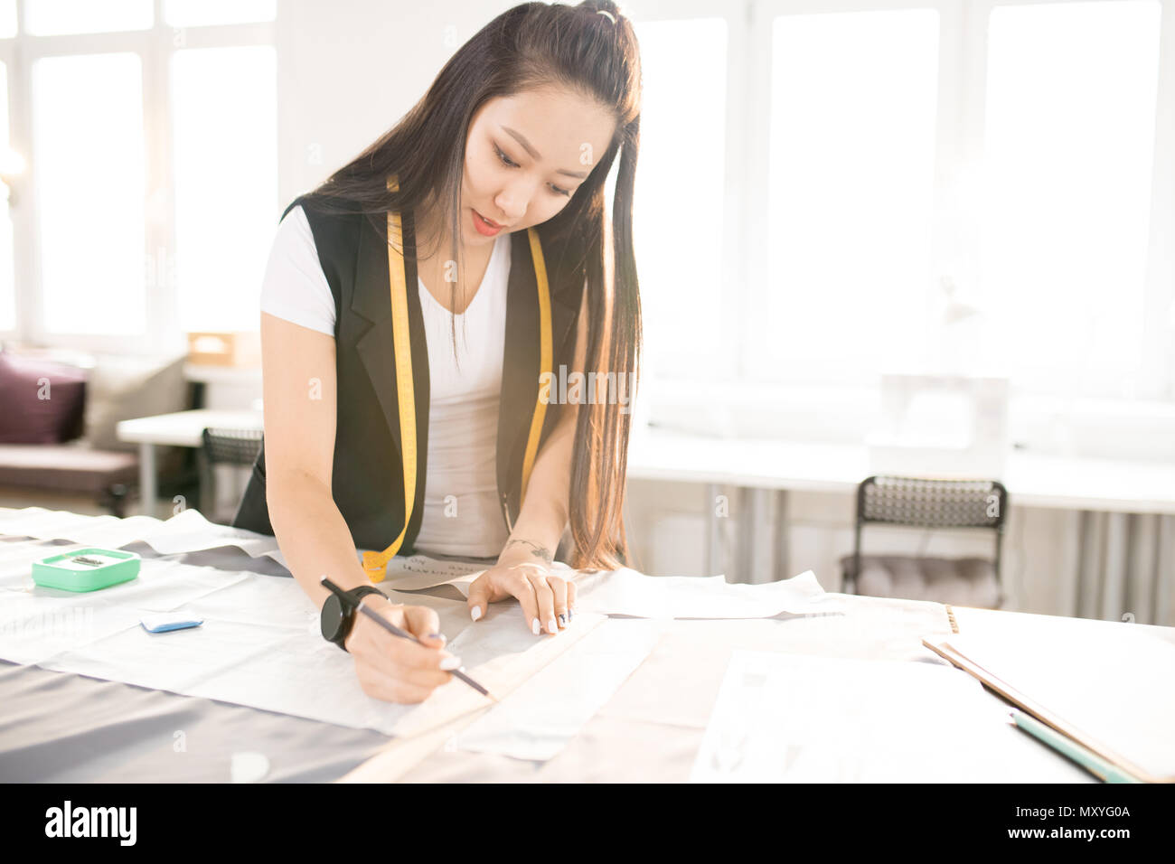 Waist up portrait of smiling Asian woman drawing tracing pattern while ...