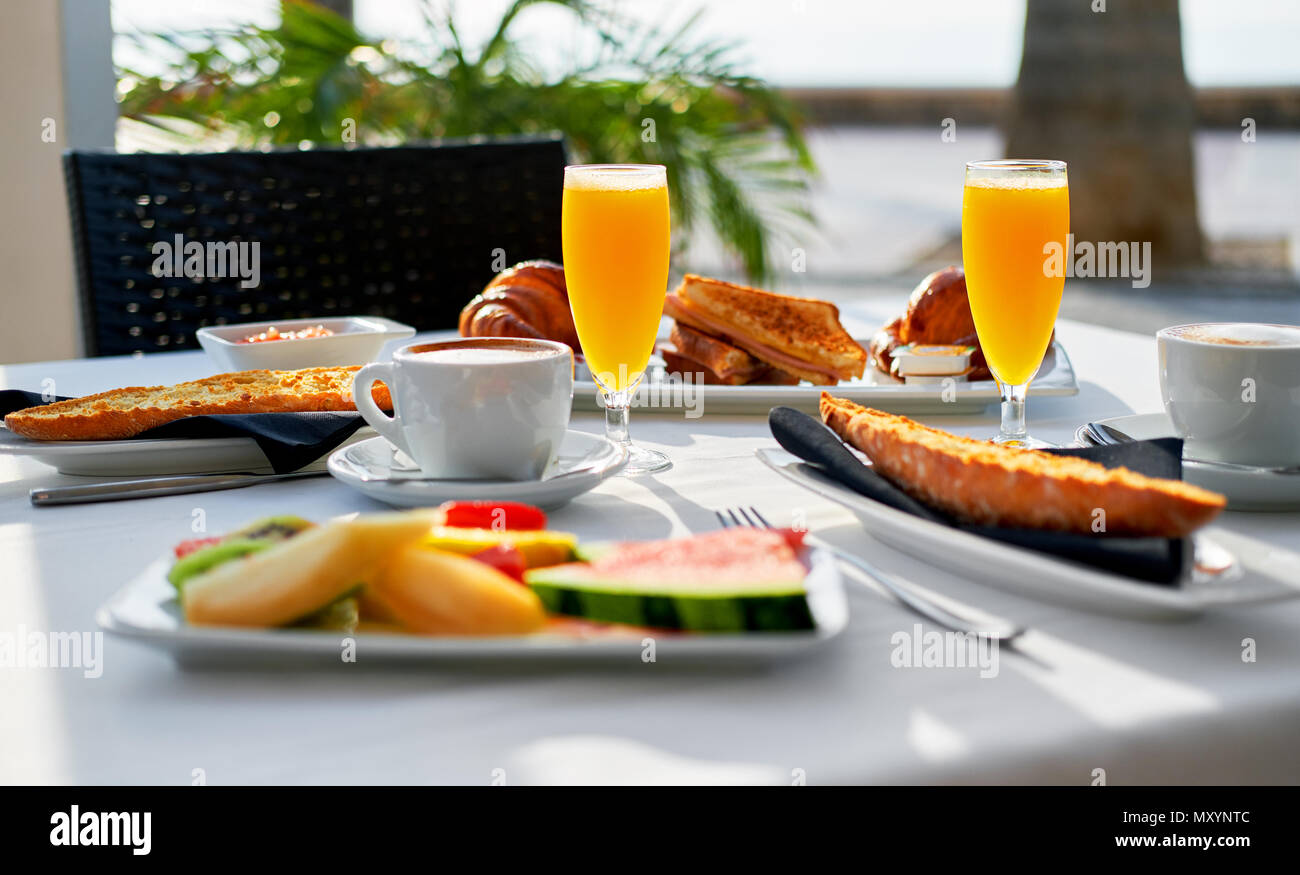 Outdoors restaurant. Table setting with classic breakfast. Orange juice ...
