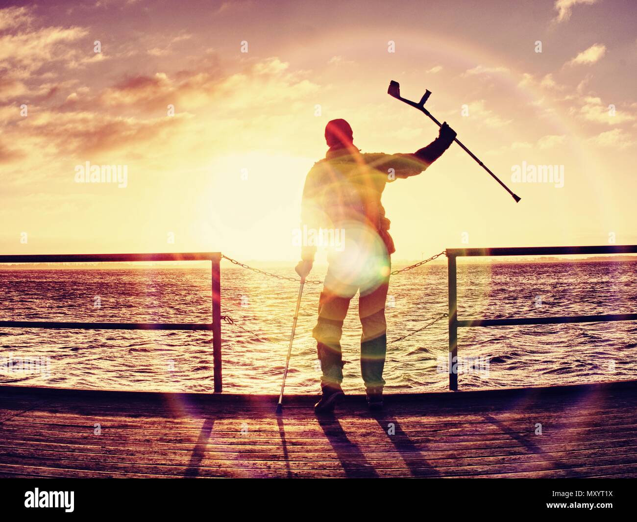 Traveler with hurt leg in bandages stay on sea bridge. Tourist with ...