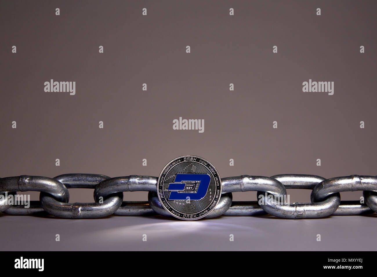 A Dash Coin sits on a white surface while a heavy steel metal chain ...